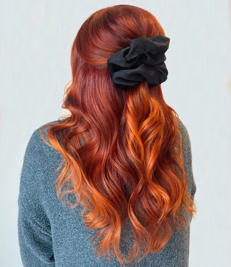 Lunghi capelli mossi con balayage rosso rame, semi raccolti con ...